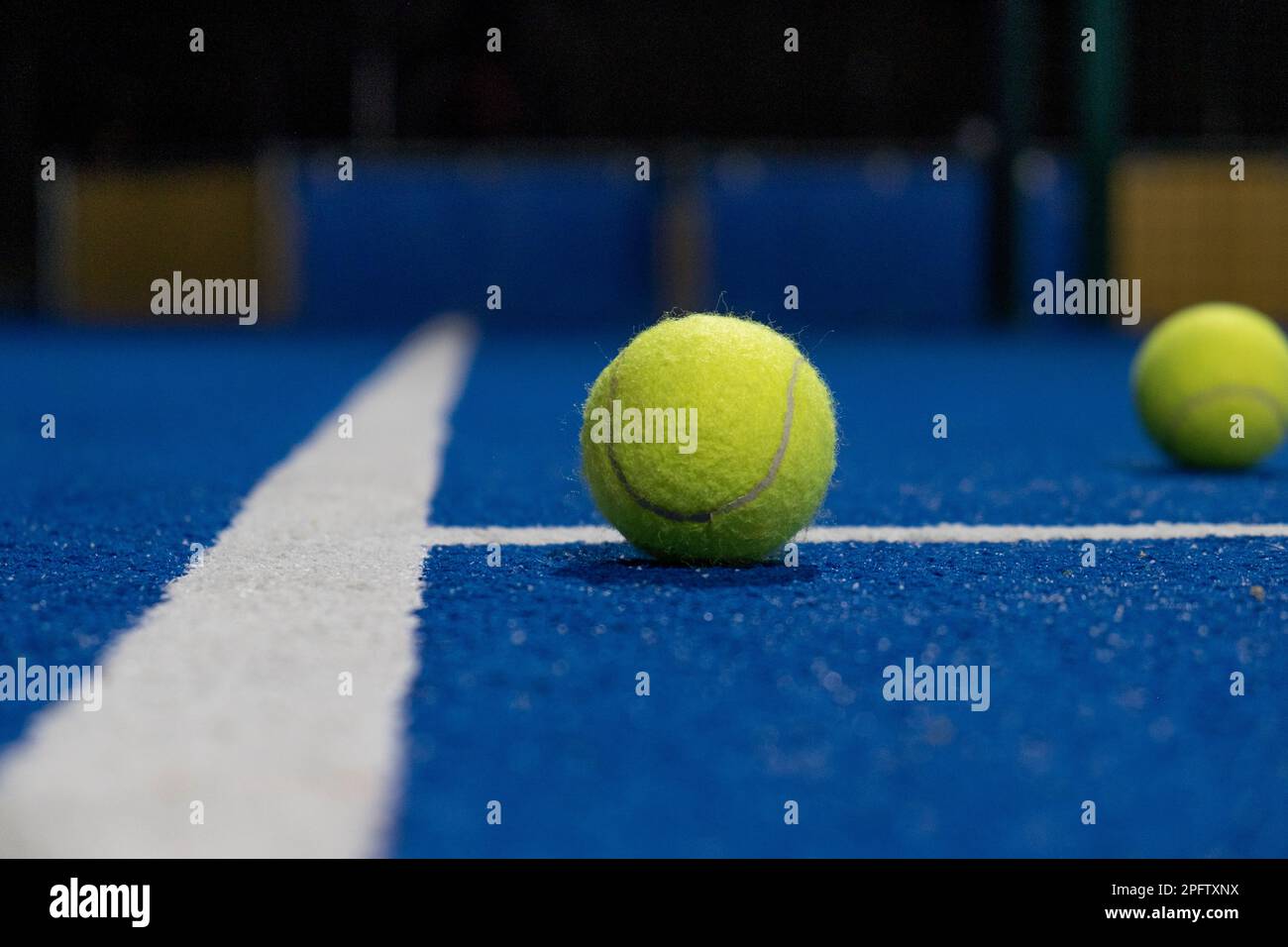 Selective focus, two balls and the line of a blue paddle tennis court ...