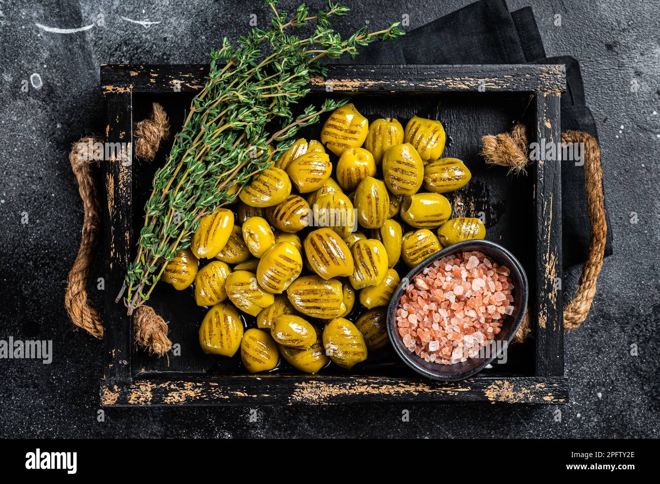 Greek Grilled olives with garlic, olive oil and spices in wooden tray ...