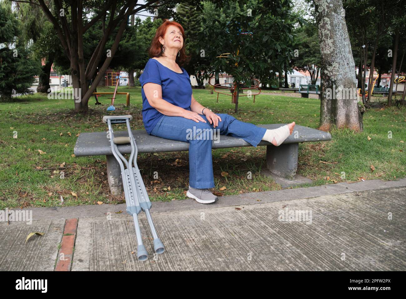 Latin mature woman with an injury sitting on a park bench with a ...