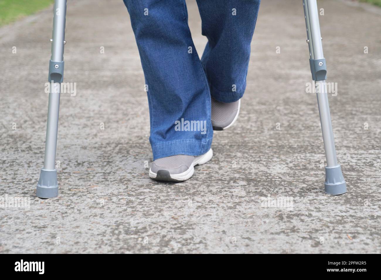 Detail of the legs and feet of an unrecognizable person walking with ...