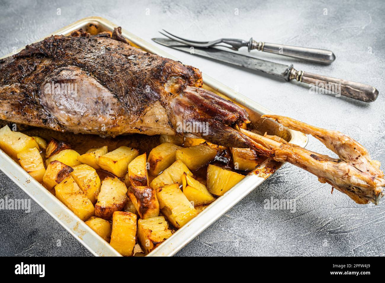 Roast lamb mutton leg with potatoes and rosemary in baking dish. White ...