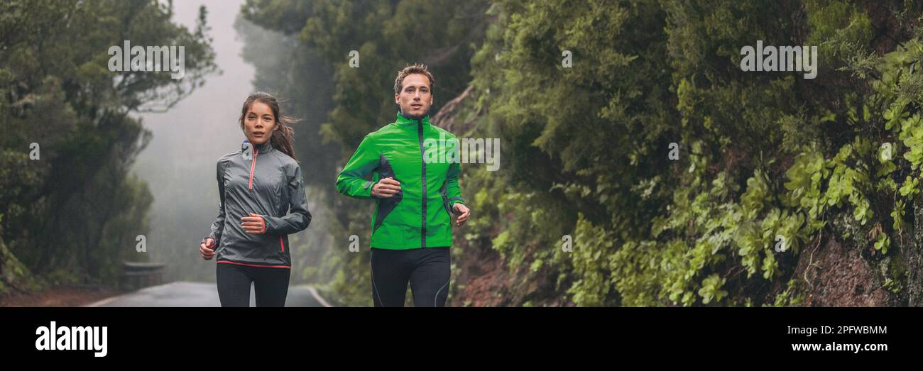 Runners jogging outside on wet trail running in the rain in autumn fall ...