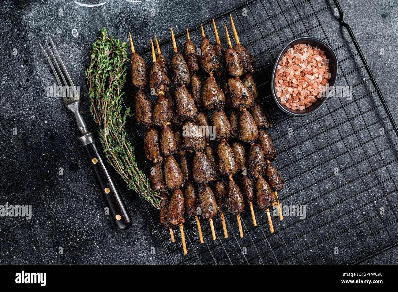 Grilled shish kebab with chicken hearts on a grill. Black background ...
