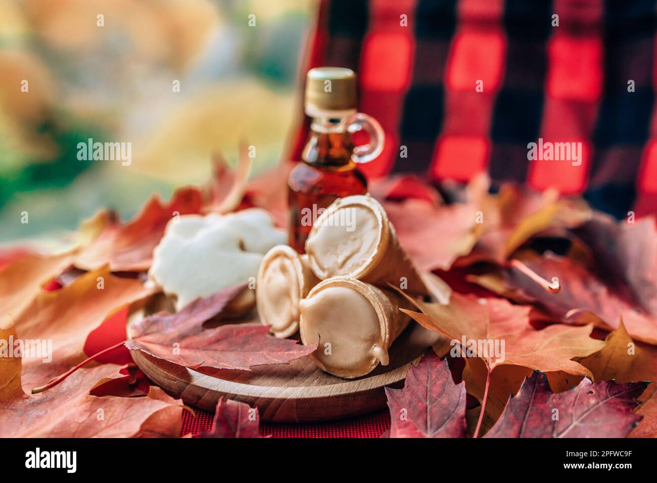 Maple syrup taffy cones dessert with traditional bottle and plaid cloth ...