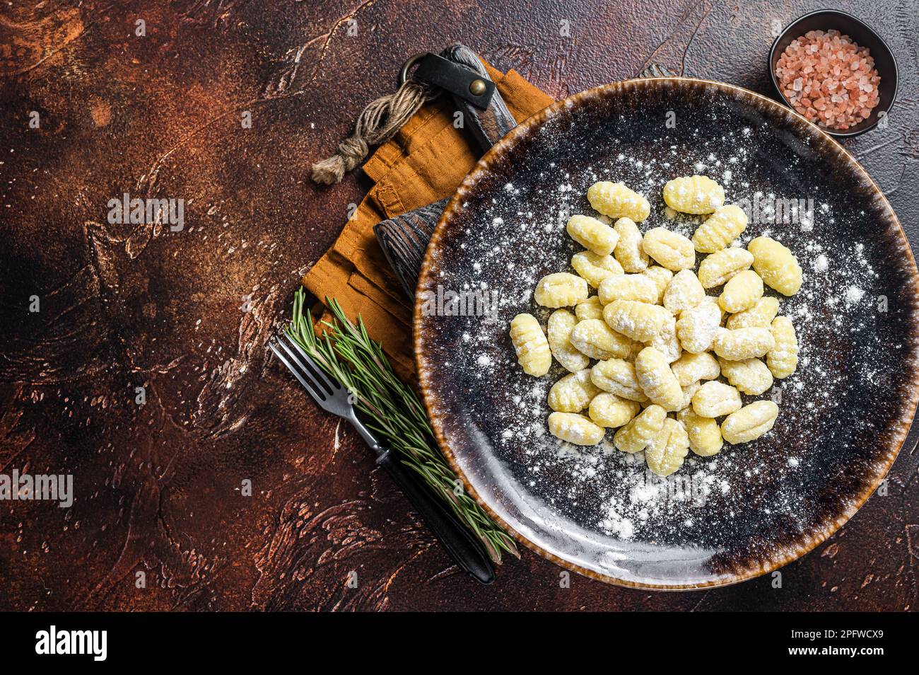 Italian gnocchi dumplings, Raw potato gnocchi on plate with thyme. Dark ...