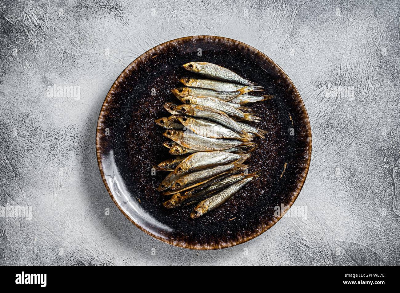 Smoked sprat fish in rustic plate. White background. Top view Stock ...