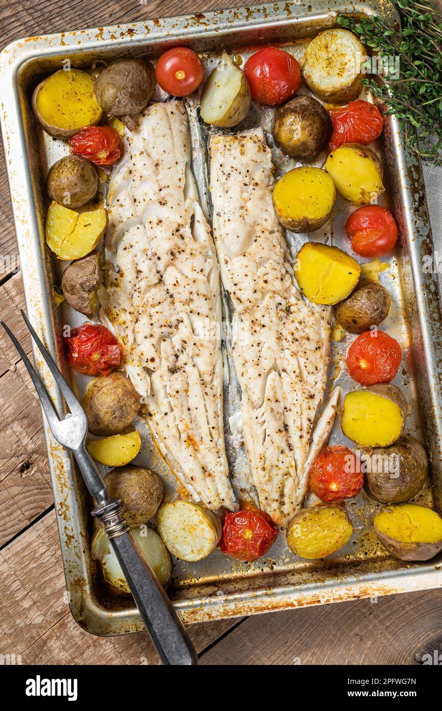 Hake fish fillet, roasted fish meat with tomato and potato. Wooden ...
