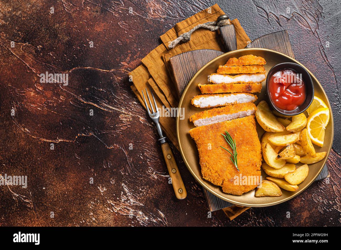 Breaded german weiner schnitzel with potato wedges. Dark background ...