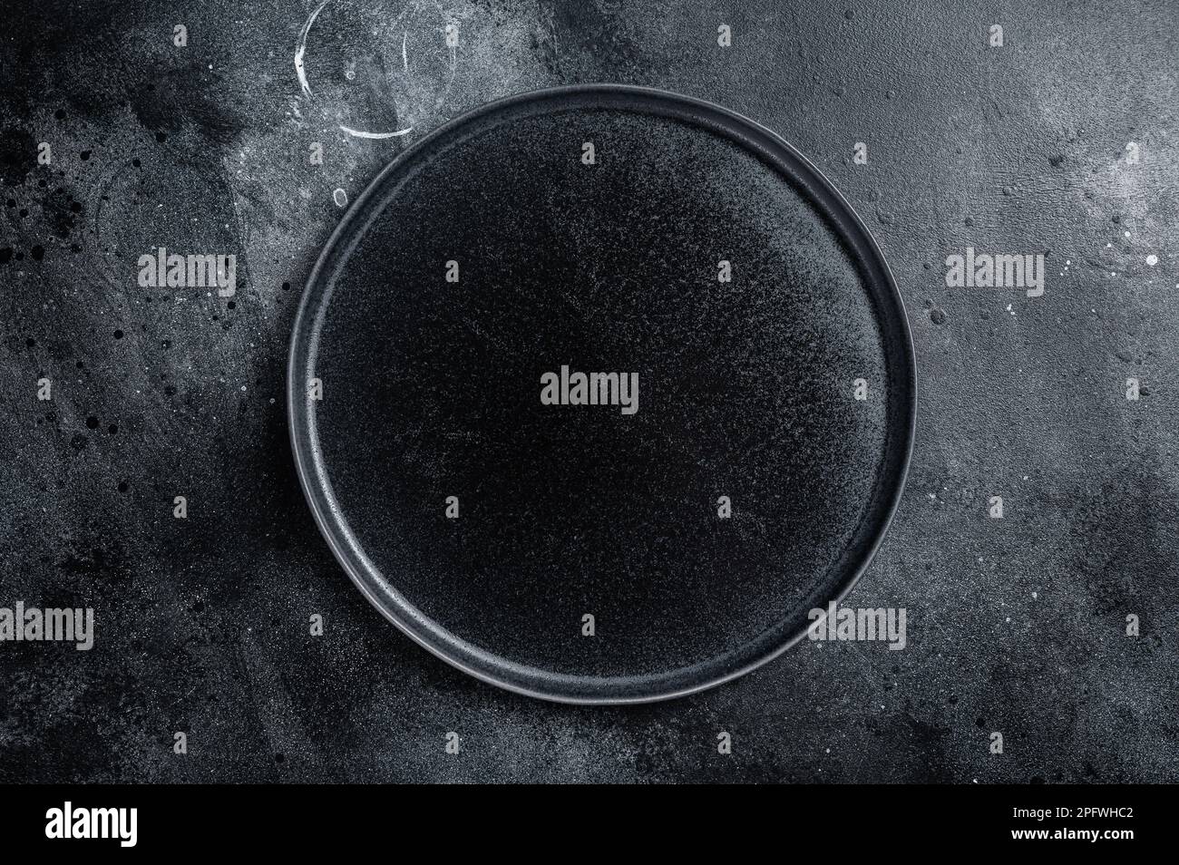 Empty black craft plate on table. Table setting. Black background. Top ...