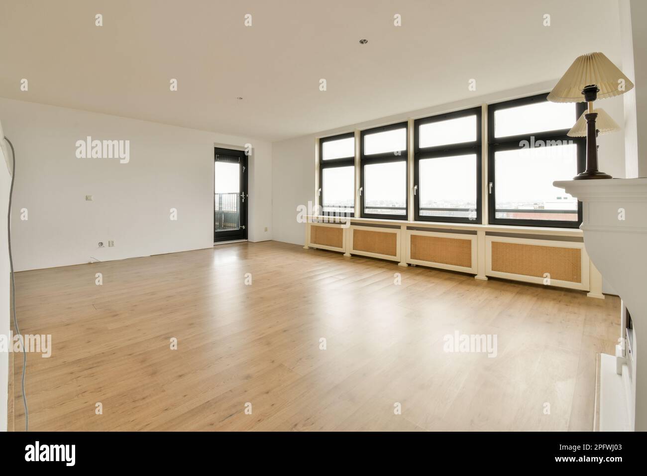 an empty living room with wood flooring and large windows looking out ...
