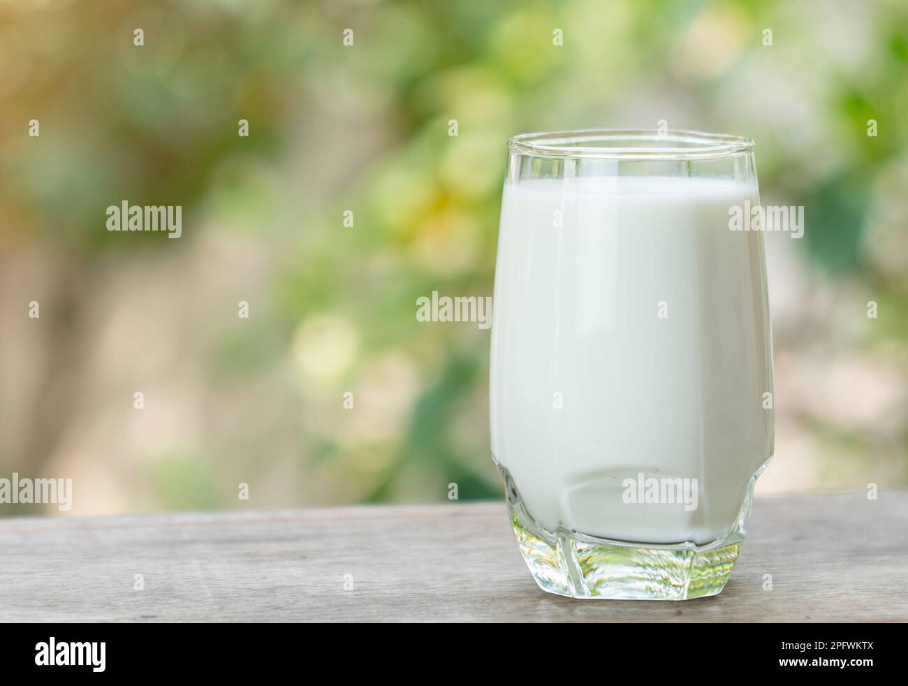 Glass of milk on out of focus green background Stock Photo - Alamy