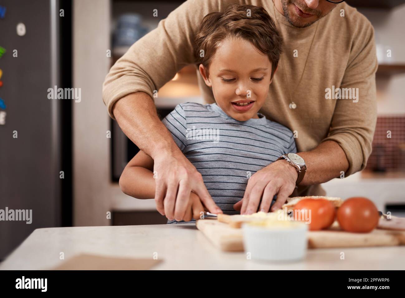 Dad is showing me how the best sandwich is made. a young boy making a ...