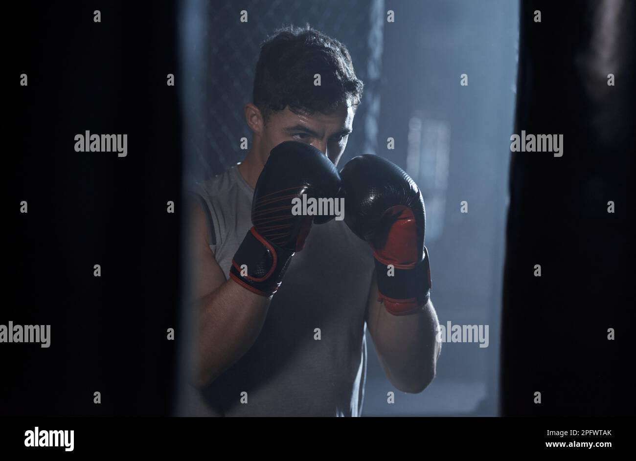 Strong is an attitude. a young man practicing his boxing routine at a ...