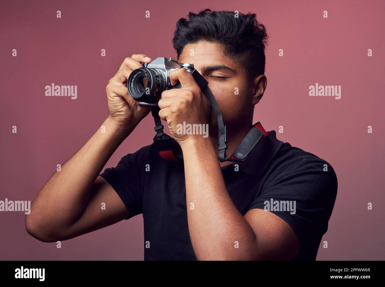 My camera goes wherever I go. Studio shot of a young man holding up a ...