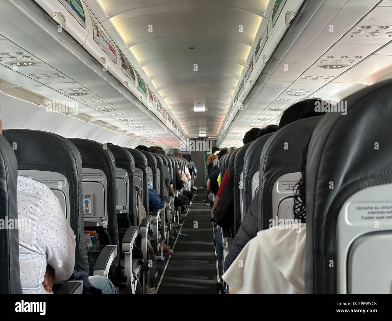 An interior shot of an airplane with passengers seated in the cabin ...