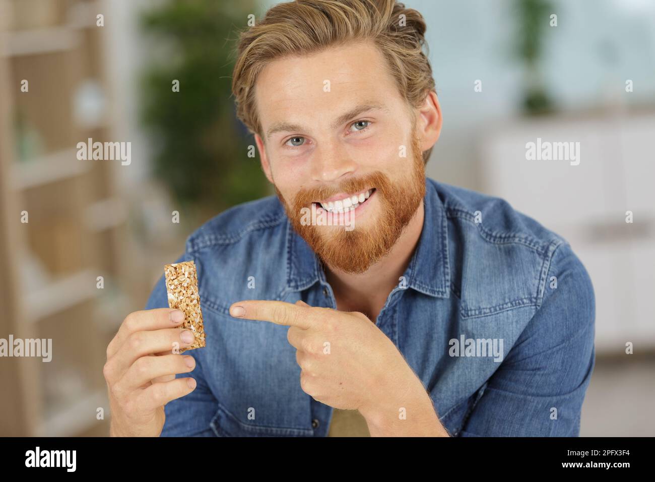 handsome young man eating cereal bar Stock Photo - Alamy