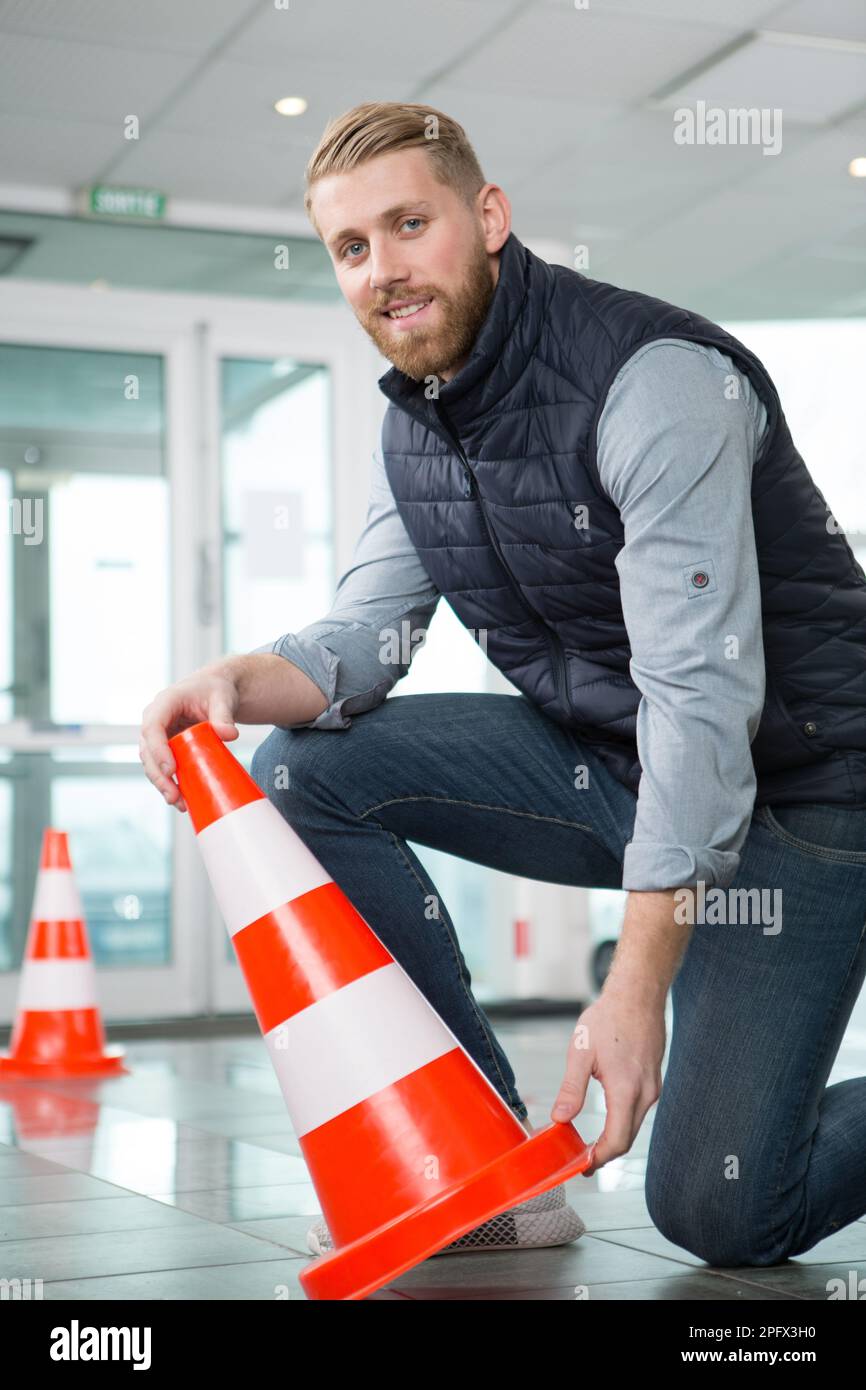 man putting down cones to warn of a slippery surface Stock Photo - Alamy