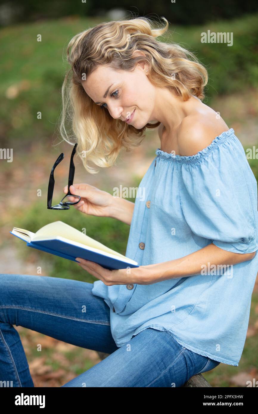 side view of pleased woman reading book in park Stock Photo - Alamy