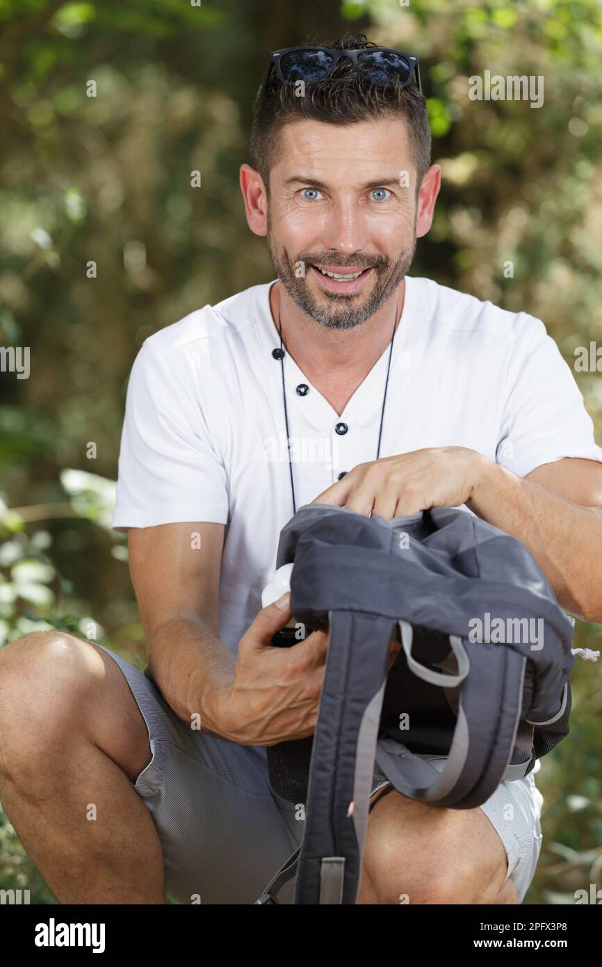 handsome man checking backpack in the woods Stock Photo - Alamy