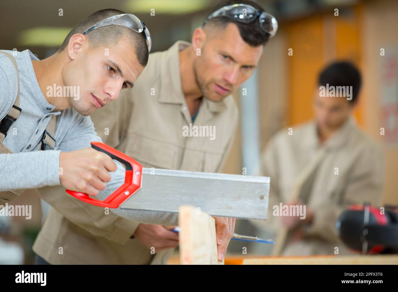 supervisor watching apprentice using a manual saw Stock Photo - Alamy