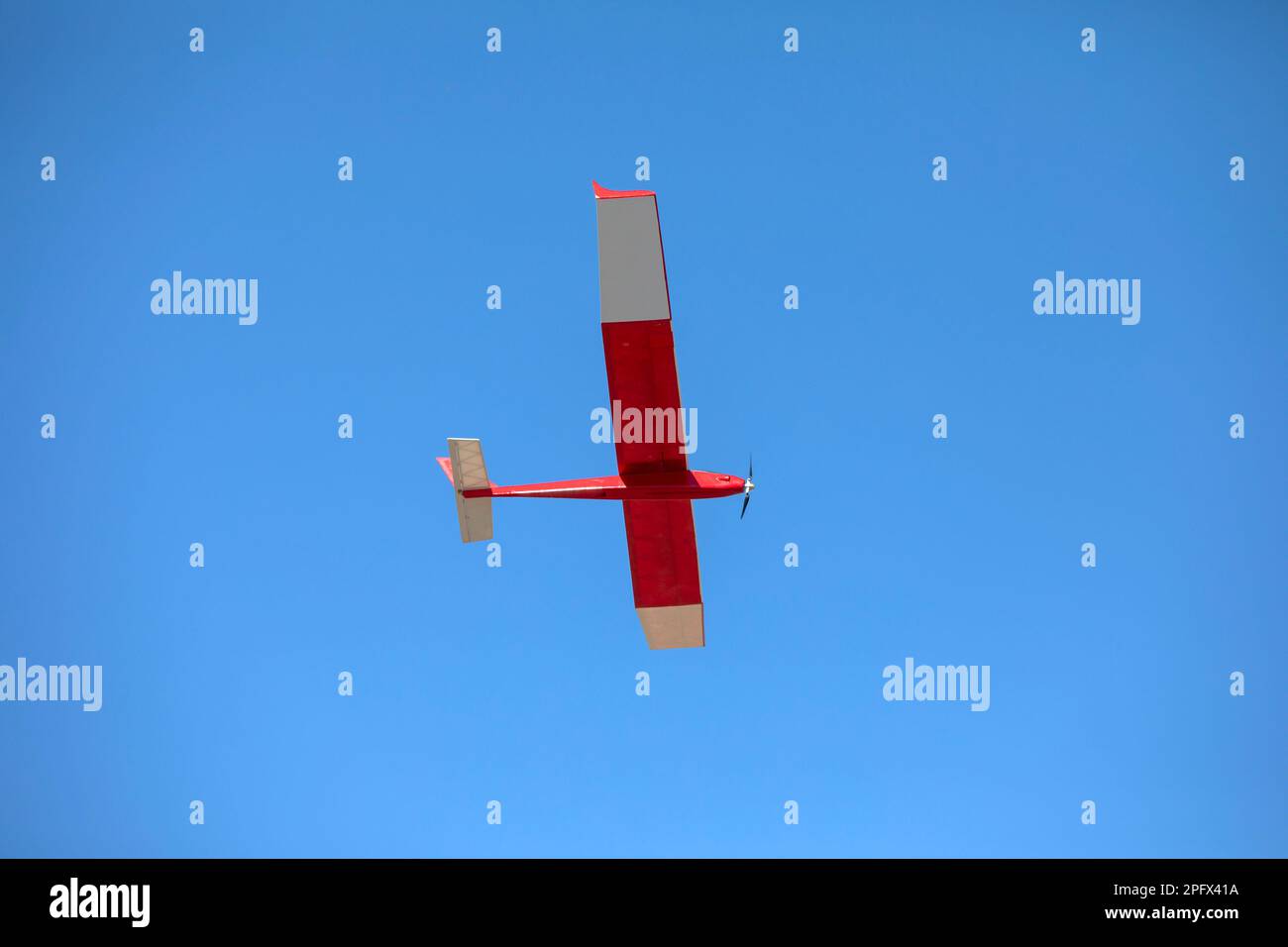 A radio controlled powered model glider soars against a blue sky ...