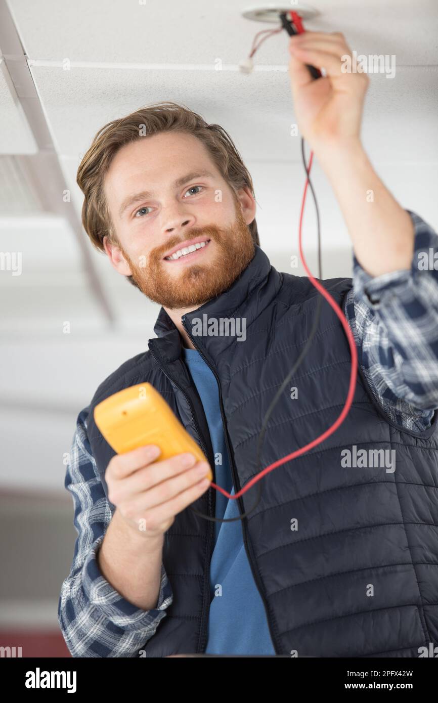 electrical technician measures the voltage in a light socket Stock ...