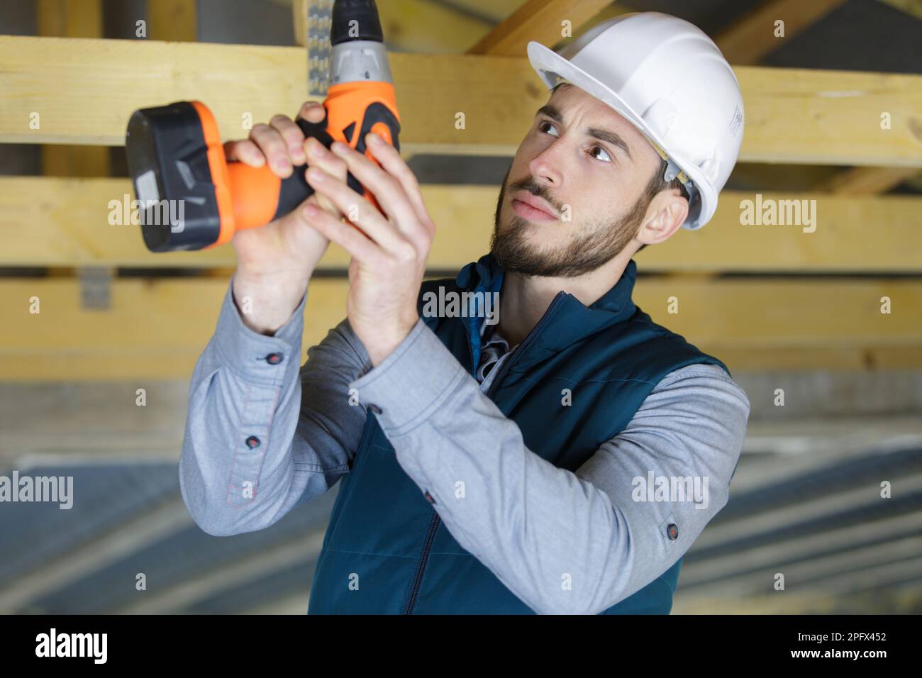 young man drilling ceiling at construction site Stock Photo - Alamy