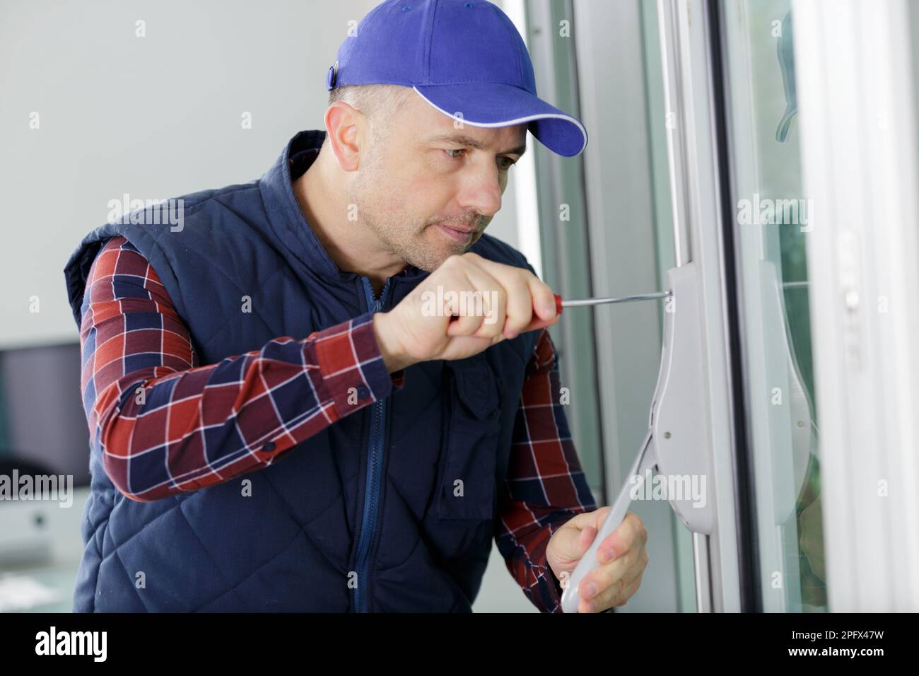 service man installing window with screwdriver Stock Photo - Alamy