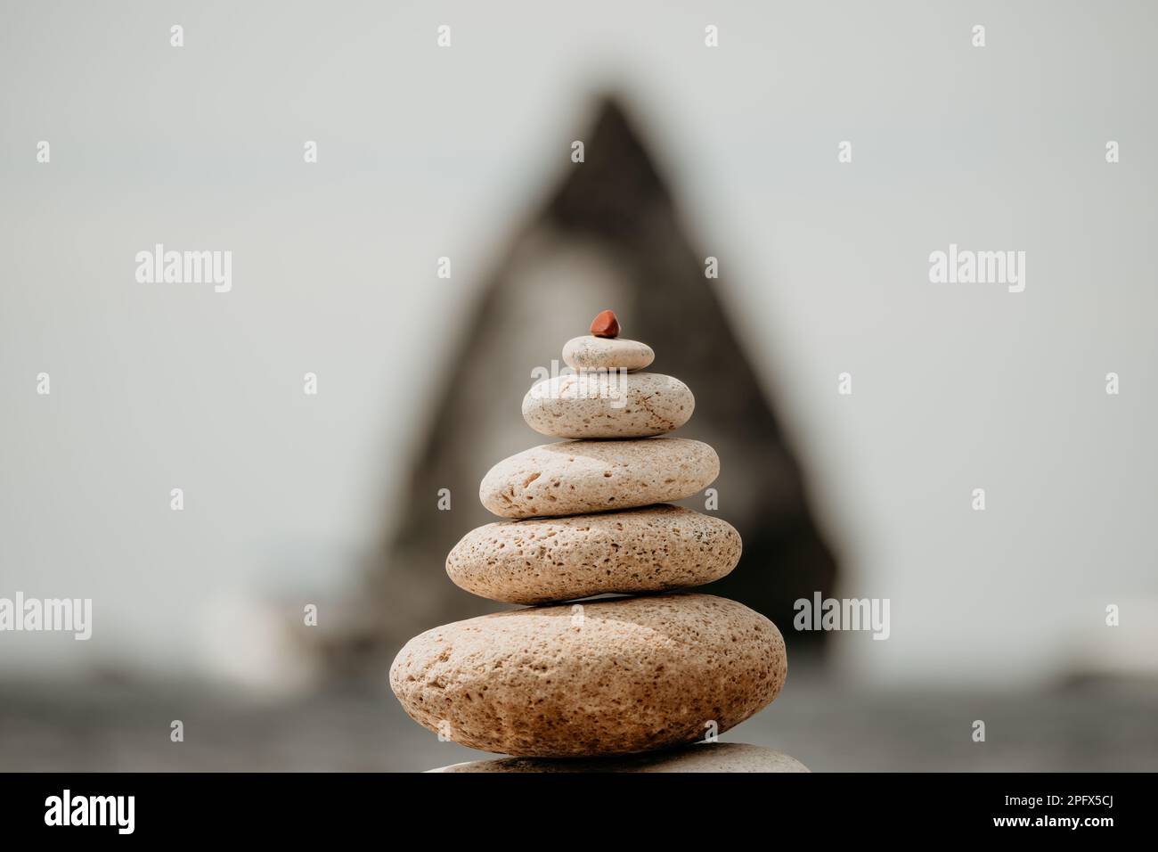 balanced rock pyramid stands tall on sea pebble beach. Selective focus ...
