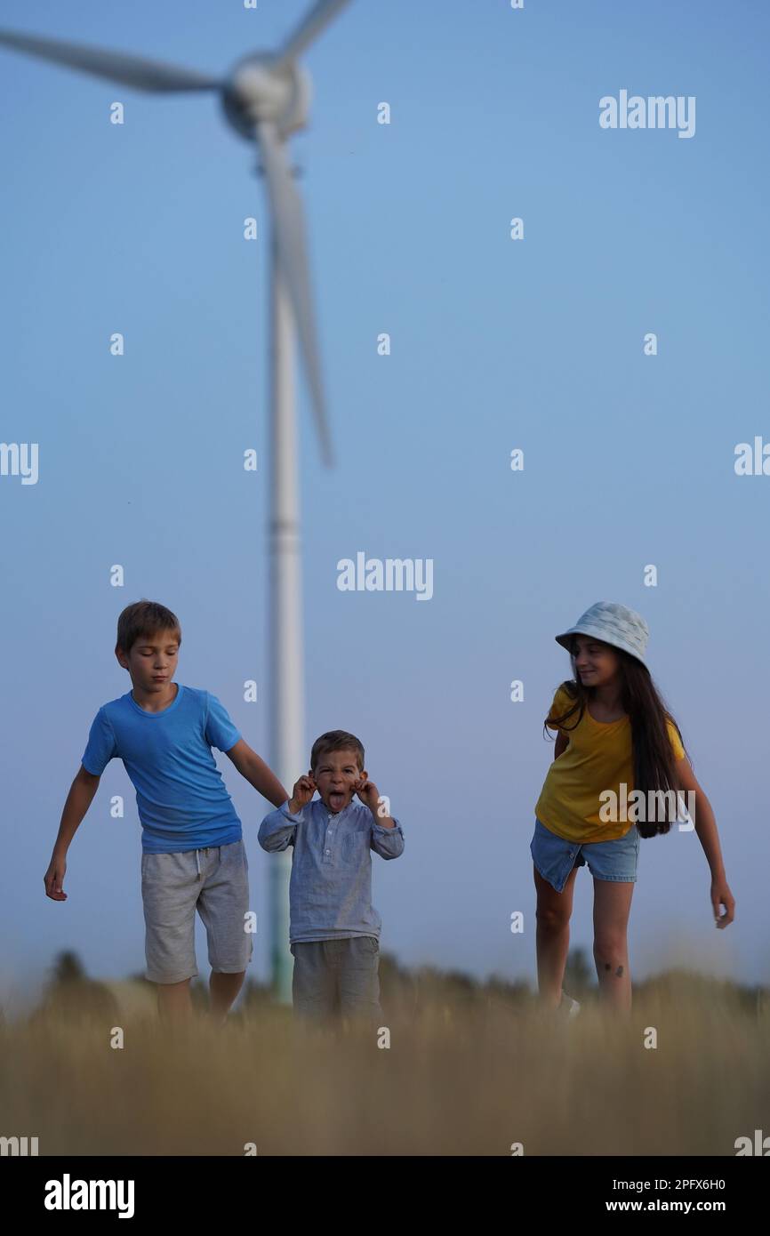 Little girl and boy are running in front of windmills. Renewable ...