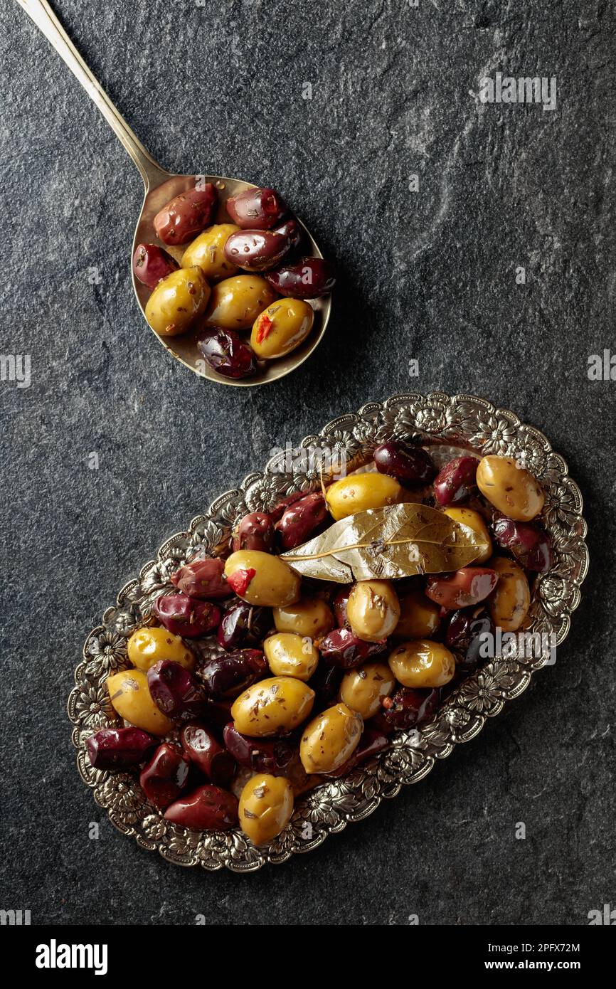 Spicy olives on a black stone table. Top view Stock Photo - Alamy