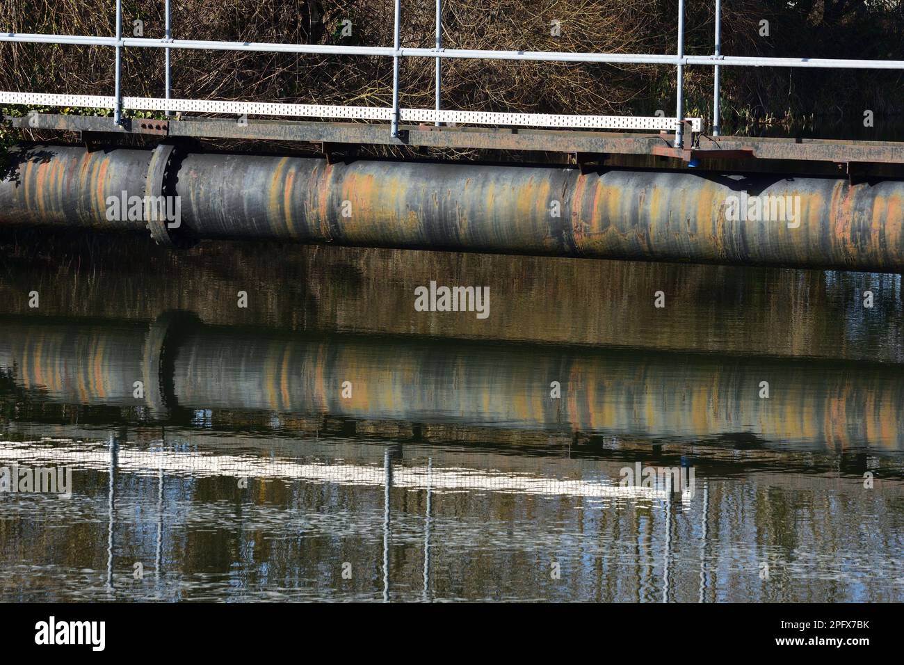 Rusty pipe and reflection on the river Stock Photo - Alamy