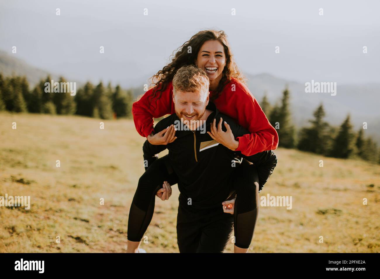 Pretty young woman riding piggyback on a boyfriend at green hills Stock ...