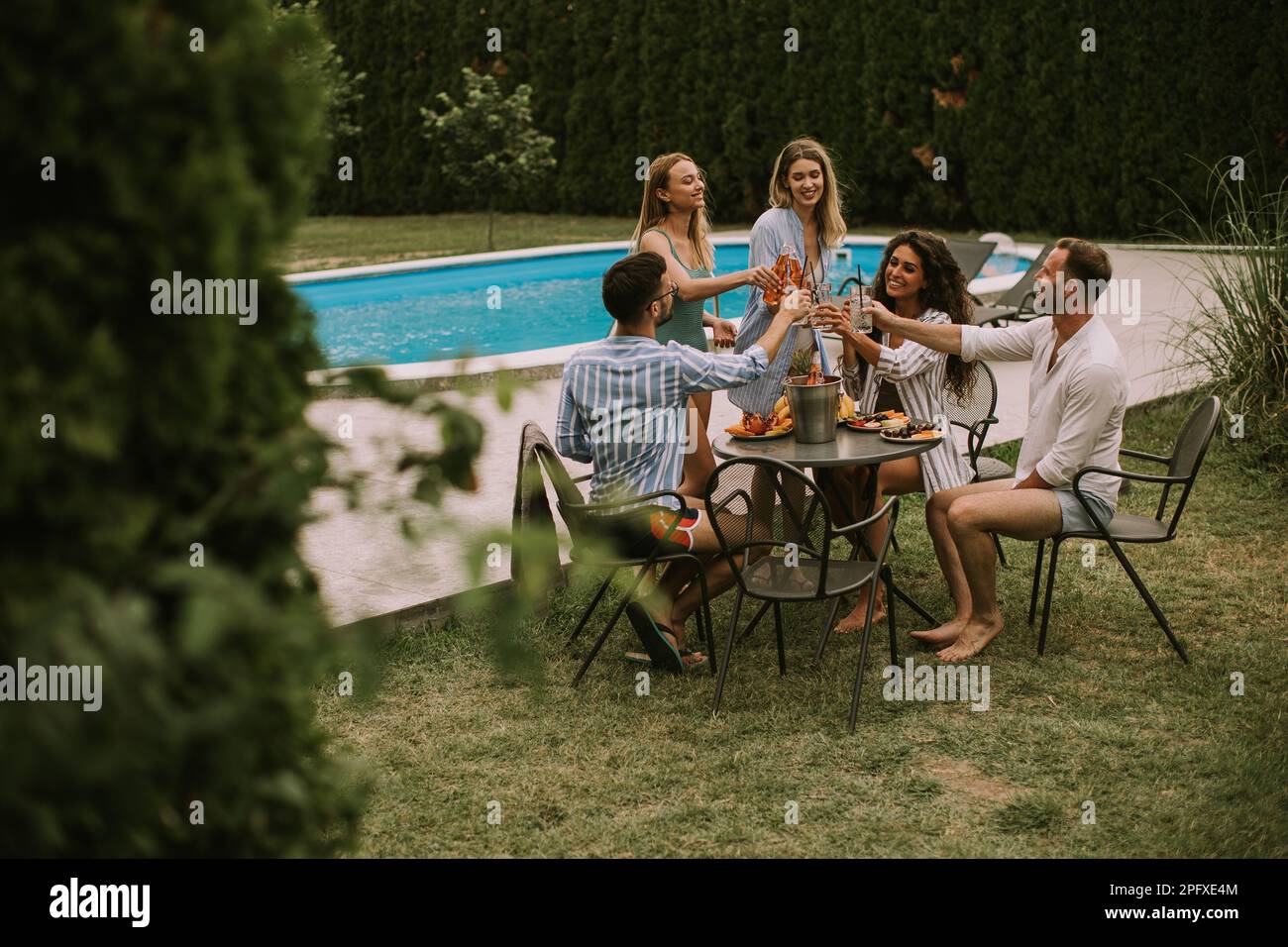 Group of happy young people cheering with cider by the pool in the ...
