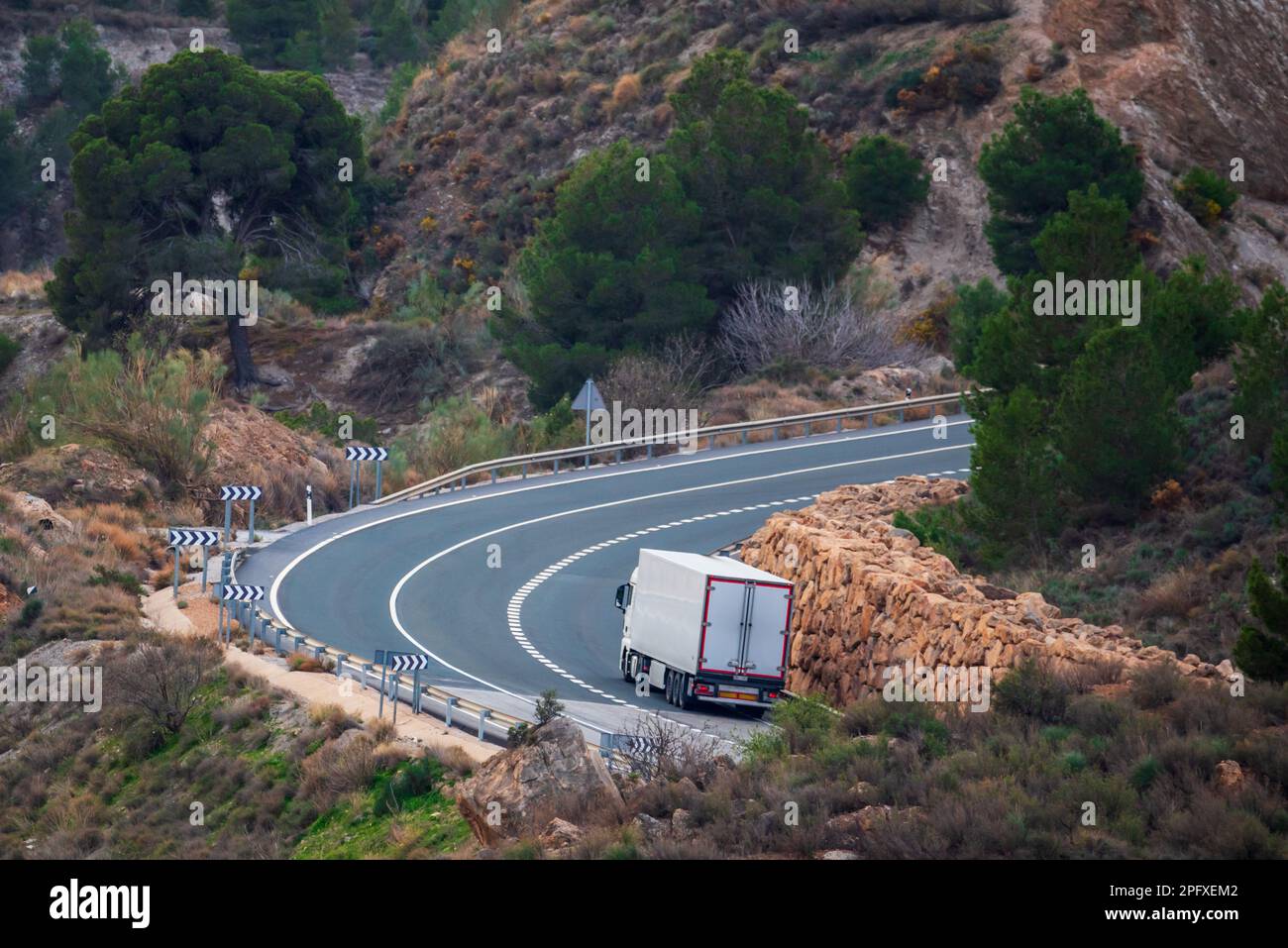 Truck with a refrigerated semi-trailer driving on a two-way road, with ...