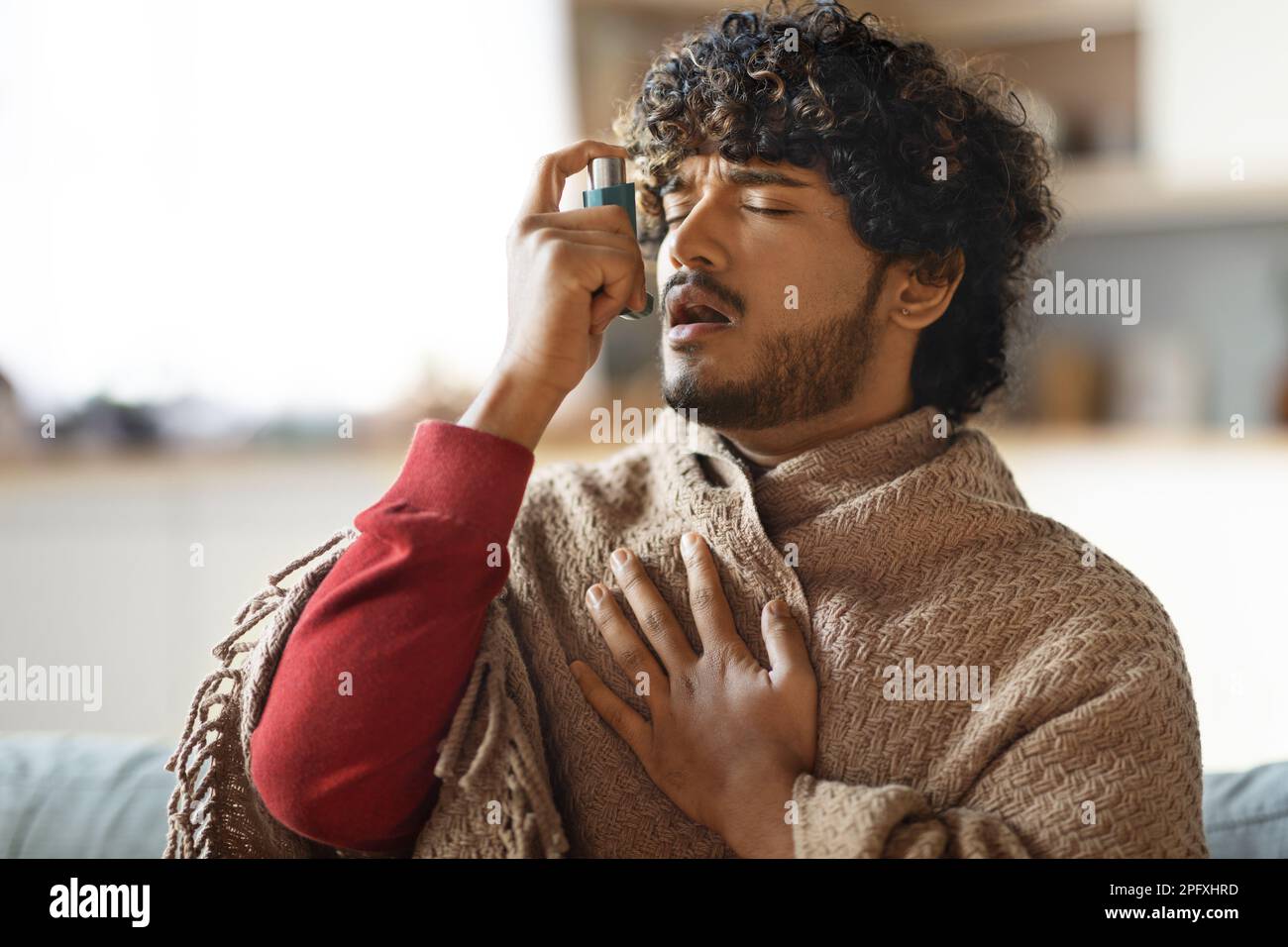 Portrait of sick young indian man using inhaler at home Stock Photo - Alamy