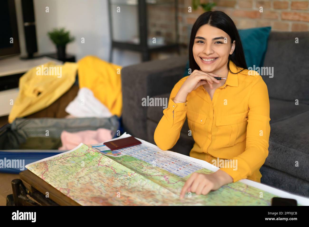 Happy young lady sitting with map and planning vacation, choosing new ...