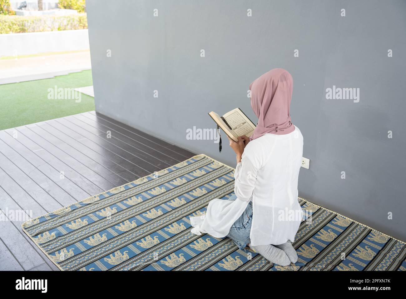 Muslim woman reading a book on gray background, in Islam study. Hand of ...