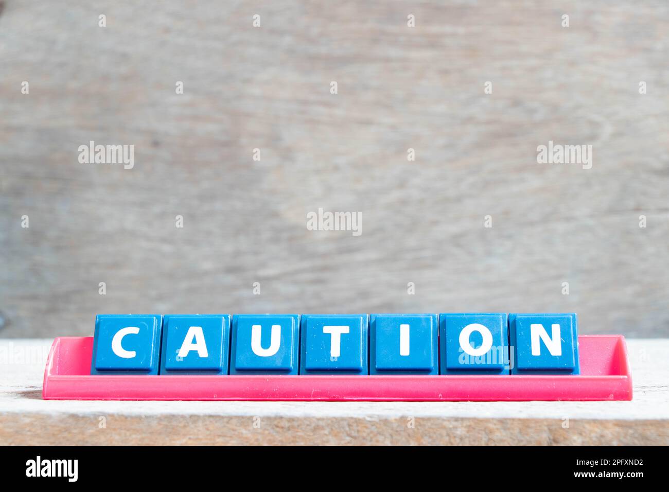 Tile alphabet letter with word caution in red color rack on wood ...
