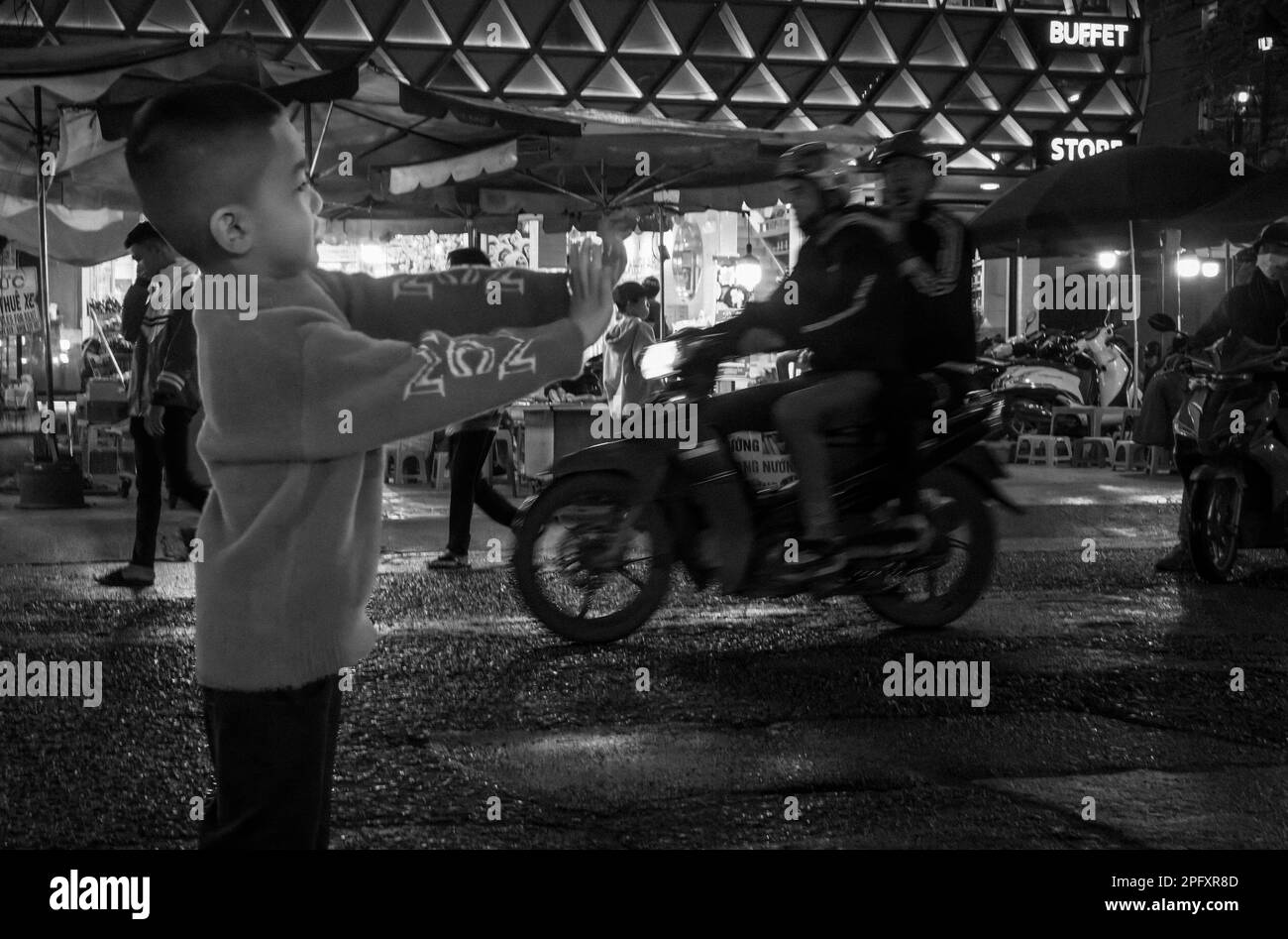 A young boy stands with his arms outstretched in the road at the night ...
