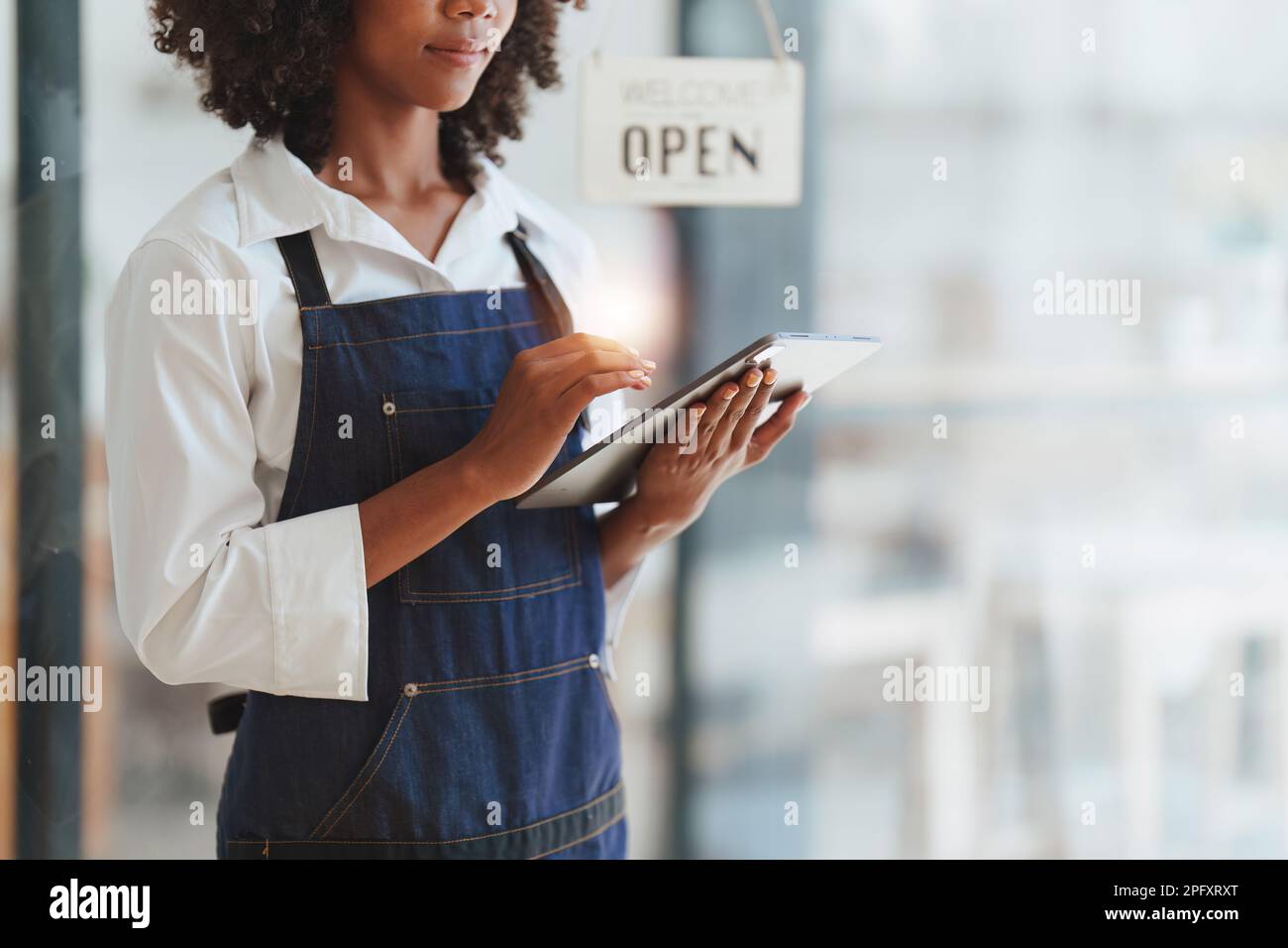 Beautiful American African cafe owner standing at cafe and using ...