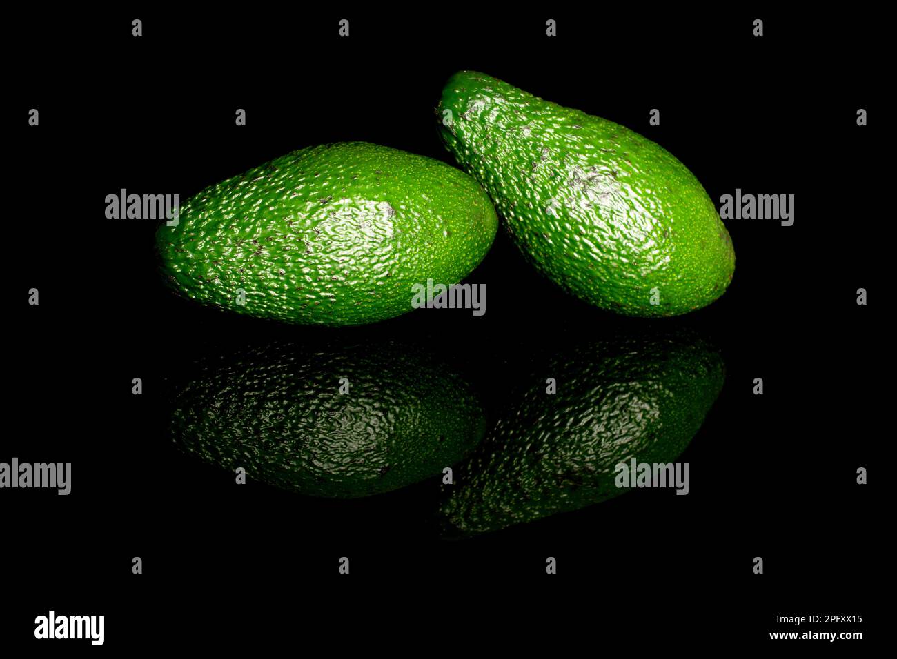 Two dark green ripe organic avocados, macro, isolated on black white ...