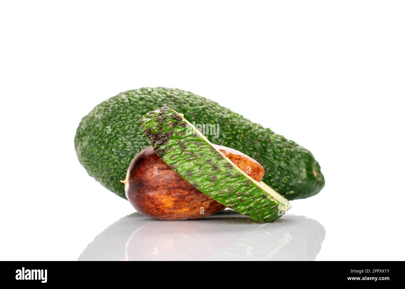 In the foreground, one round whole brown avocado pit is in focus ...