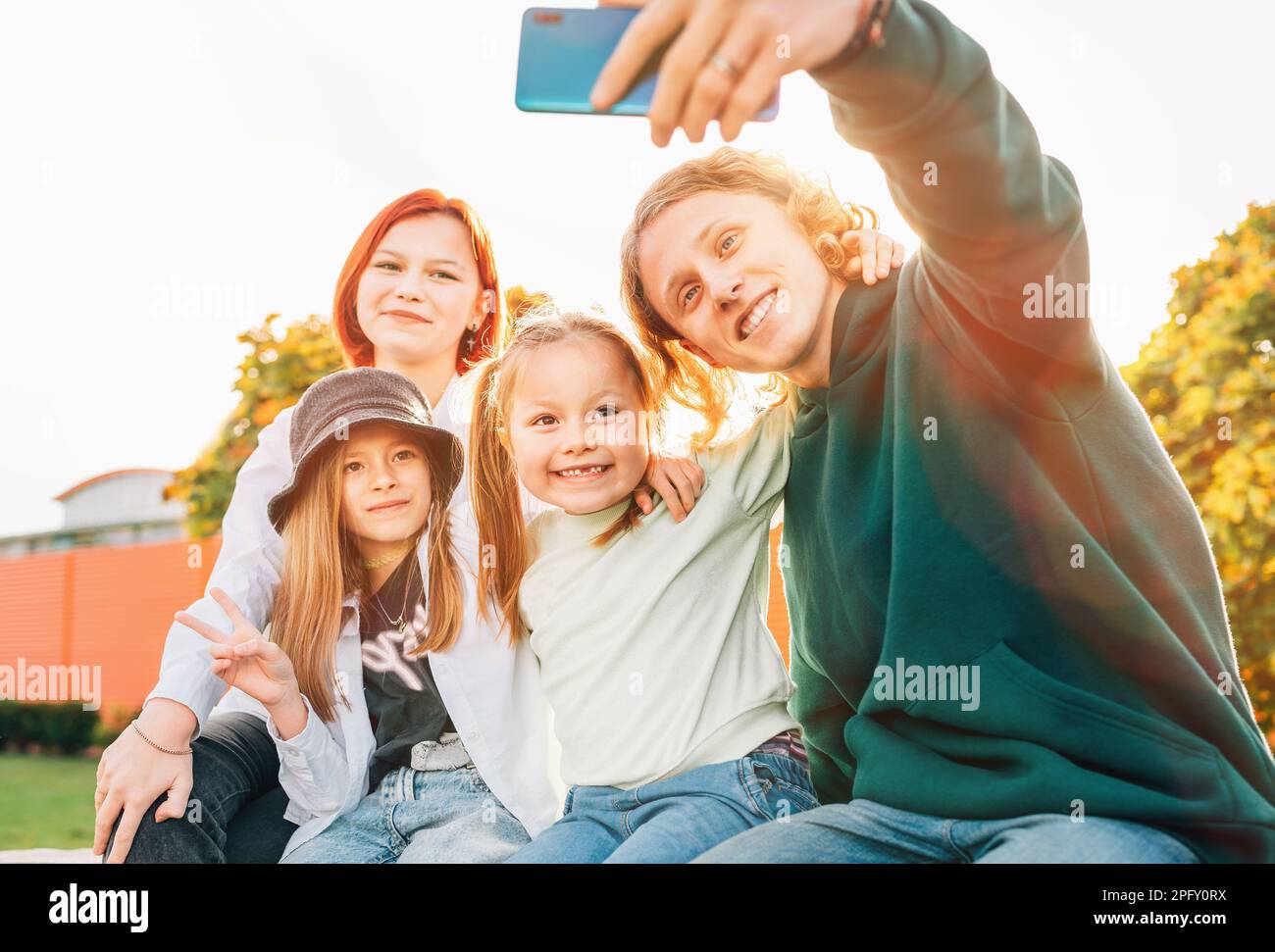 Portraits of three smiling sisters and brother teen taking selfie ...