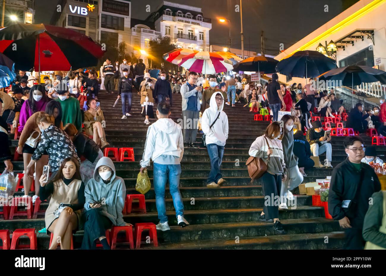 Young Vietnamese people gather with friends to sit on steps overlooking ...