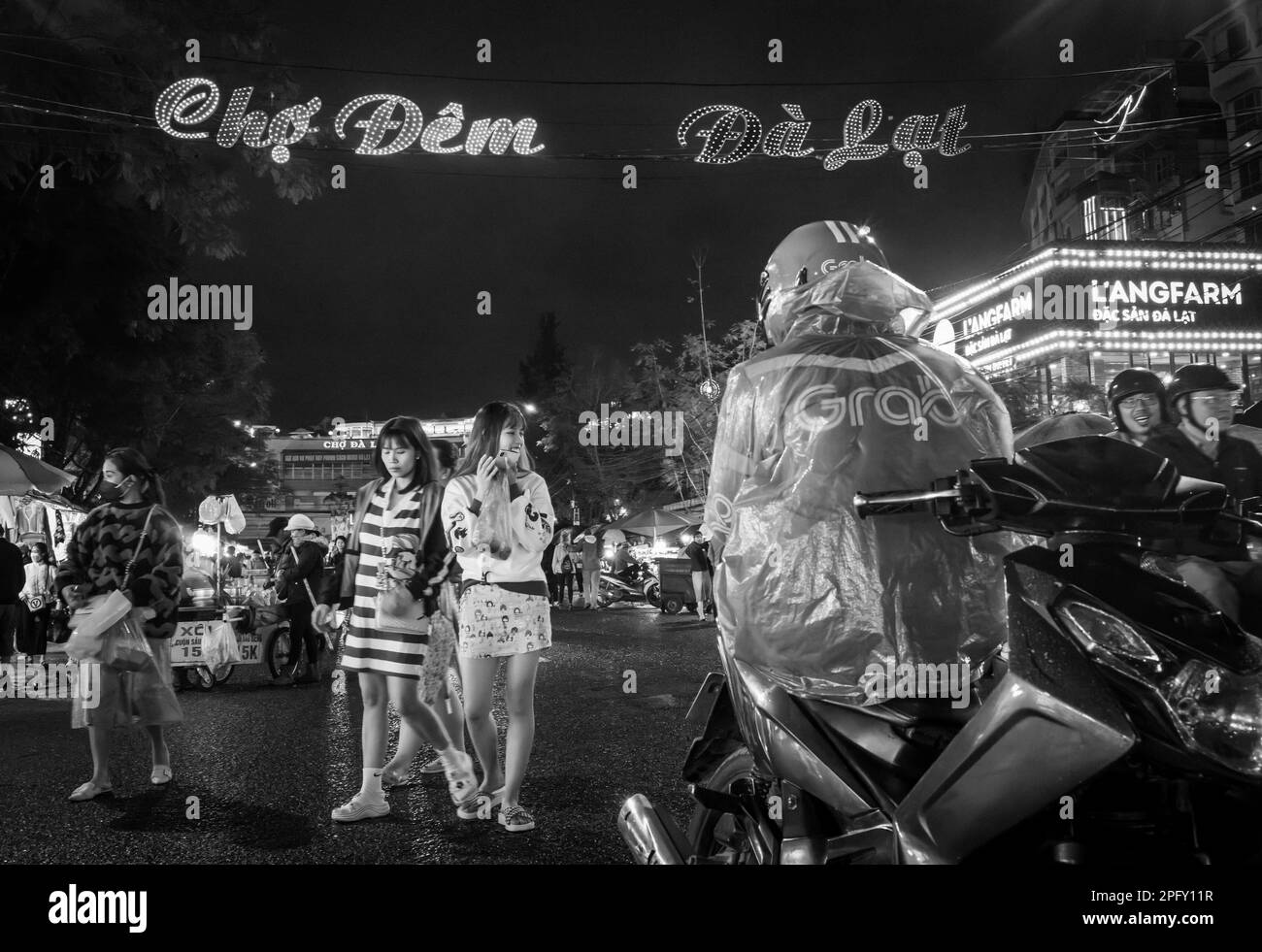 Two young Vietnamese girls walk towards a Grab motorcycle taxi driver ...