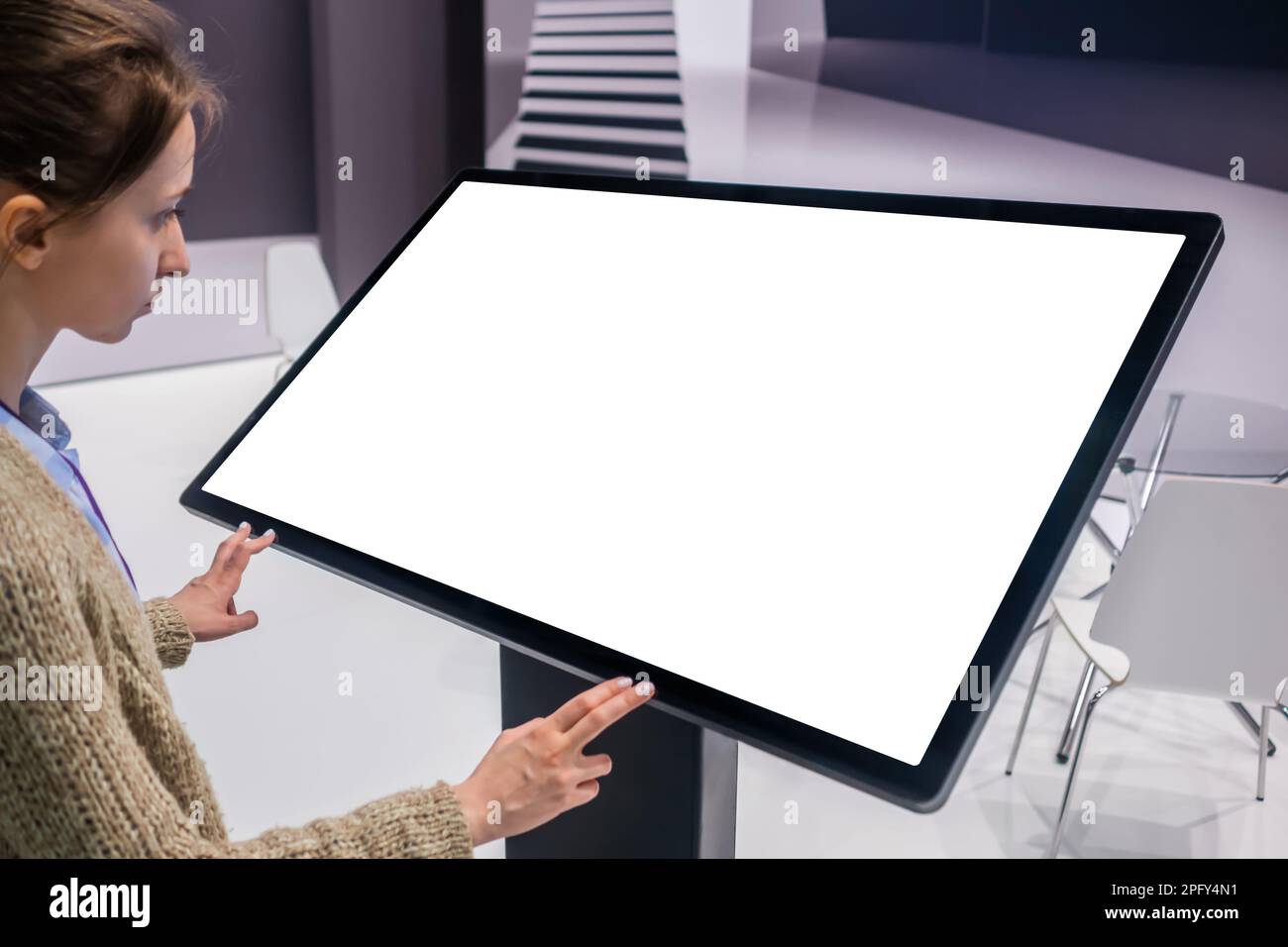 Woman using interactive empty white touchscreen display kiosk at ...