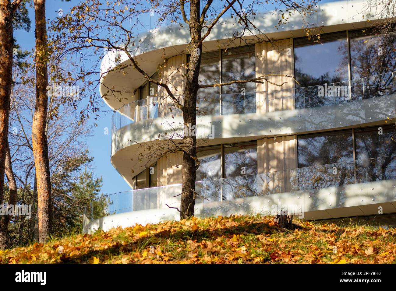 A building with glazed windows and yellow birch trees in front of the ...