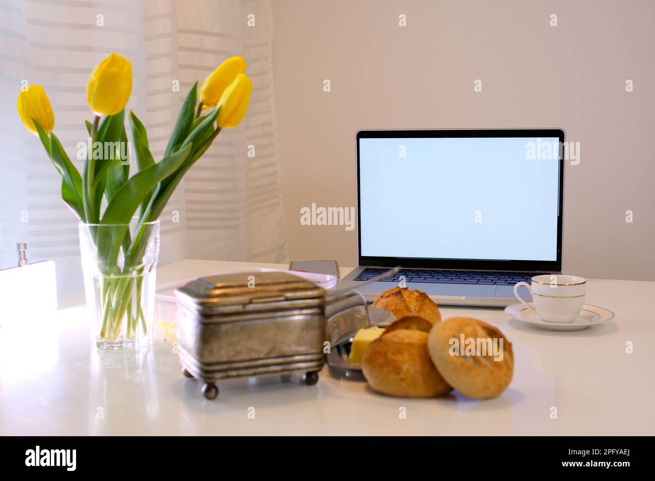 on table breakfast Yellow tulips laptop with a white screen for ...