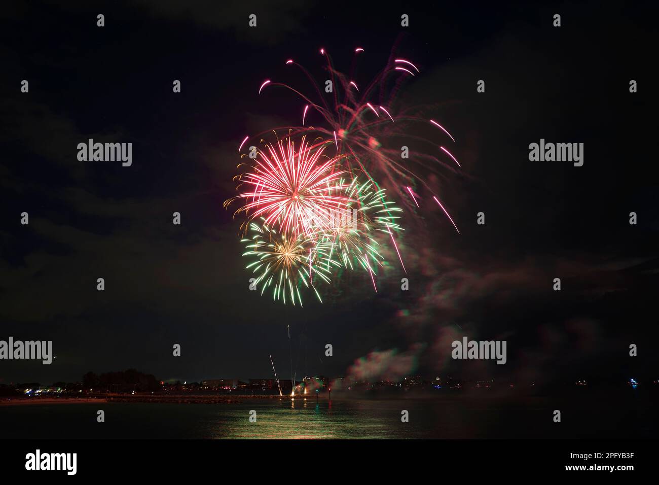 Aerial view of bright fireworks exploding with colorful lights over sea ...